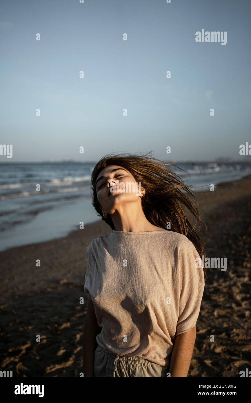 Woman tossing hair while standing at beach Stock Photo - Alamy