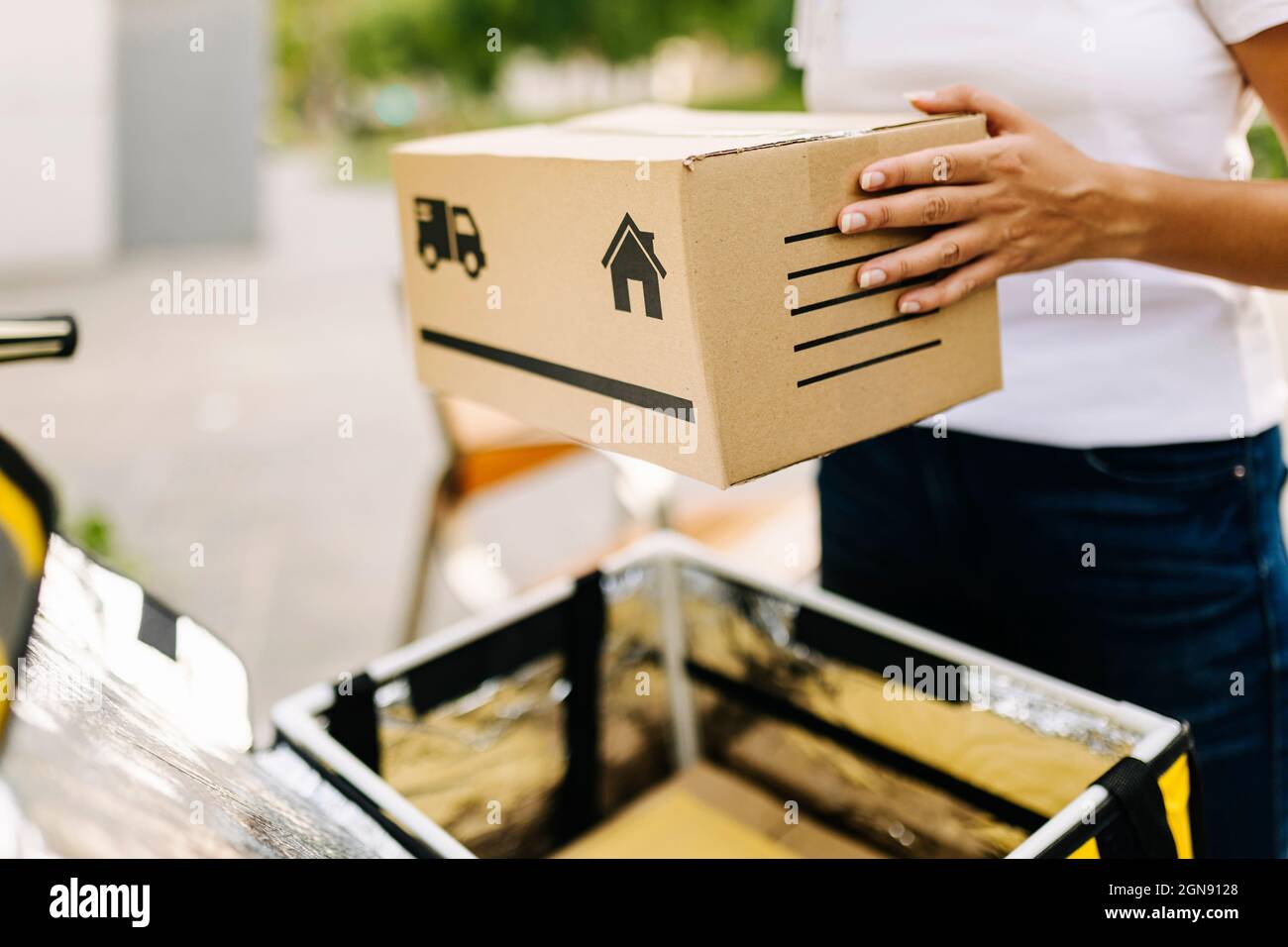 Female delivery person removing box from backpack Stock Photo - Alamy