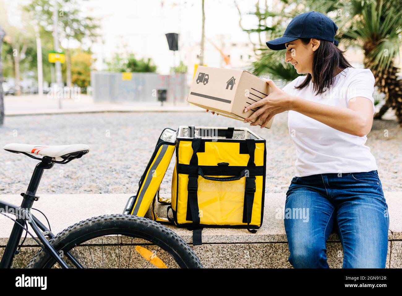 Delivery woman removing package from backpack while sitting on ...