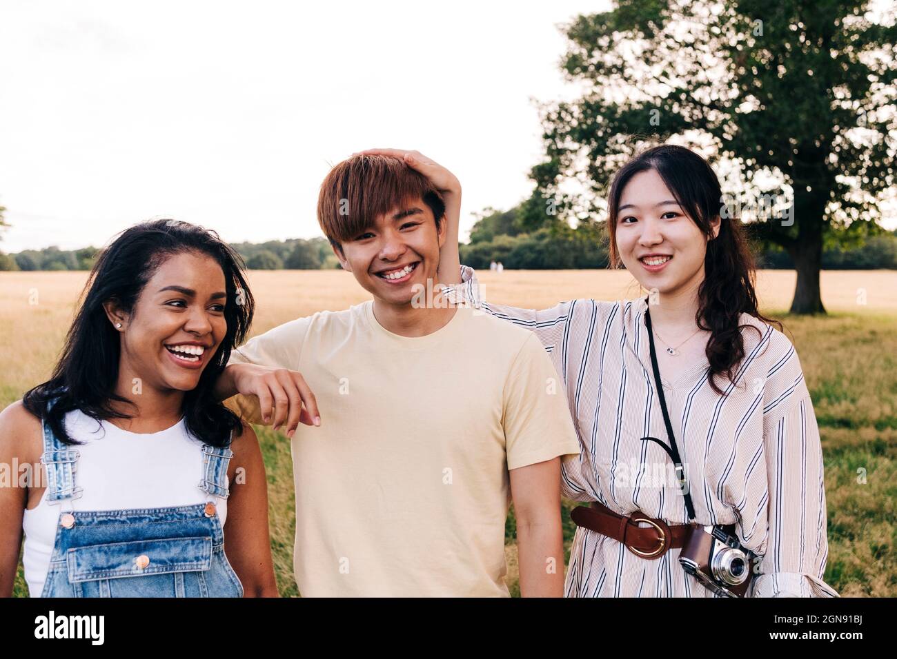 Cheerful friends standing together at park Stock Photo - Alamy