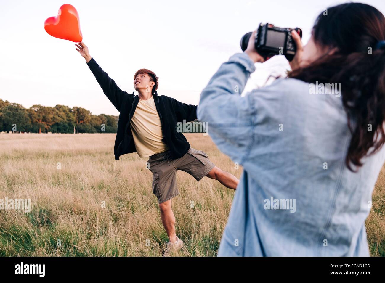 Woman photographing man catching balloon at park Stock Photo - Alamy