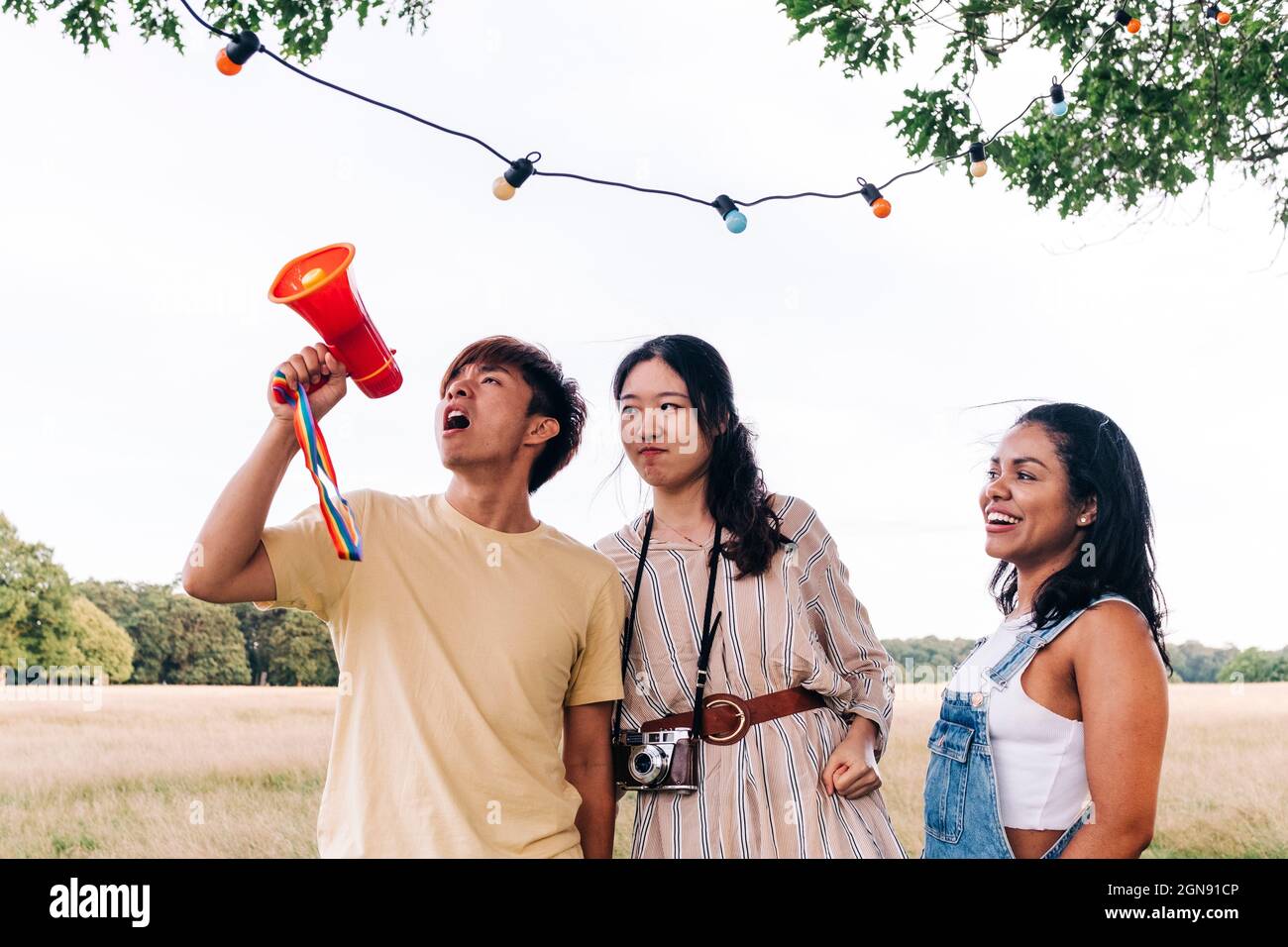 Man using megaphone while standing with friends at park Stock Photo - Alamy