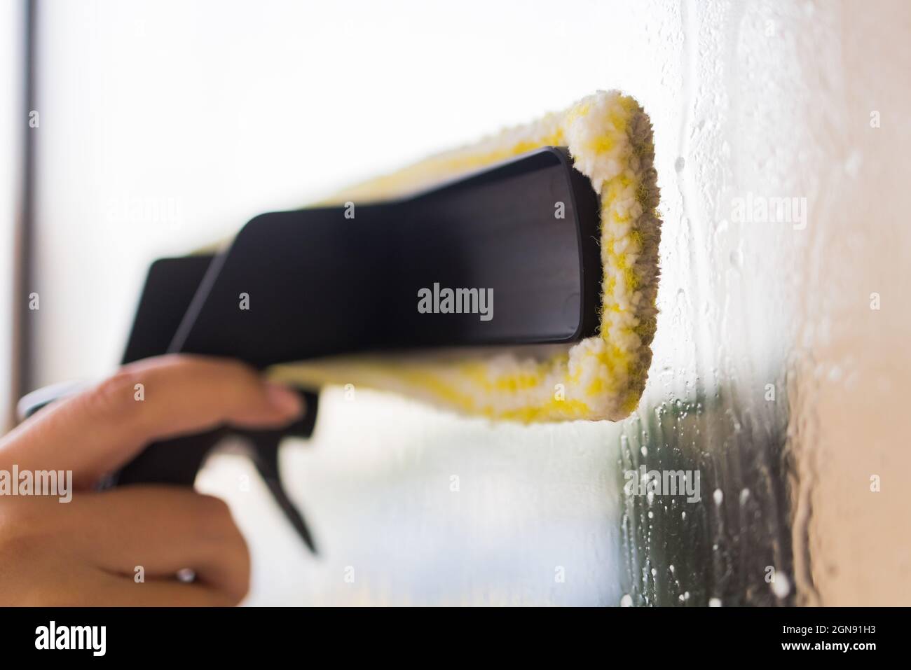 Beautiful young housewife in working clothes washing windows by ...
