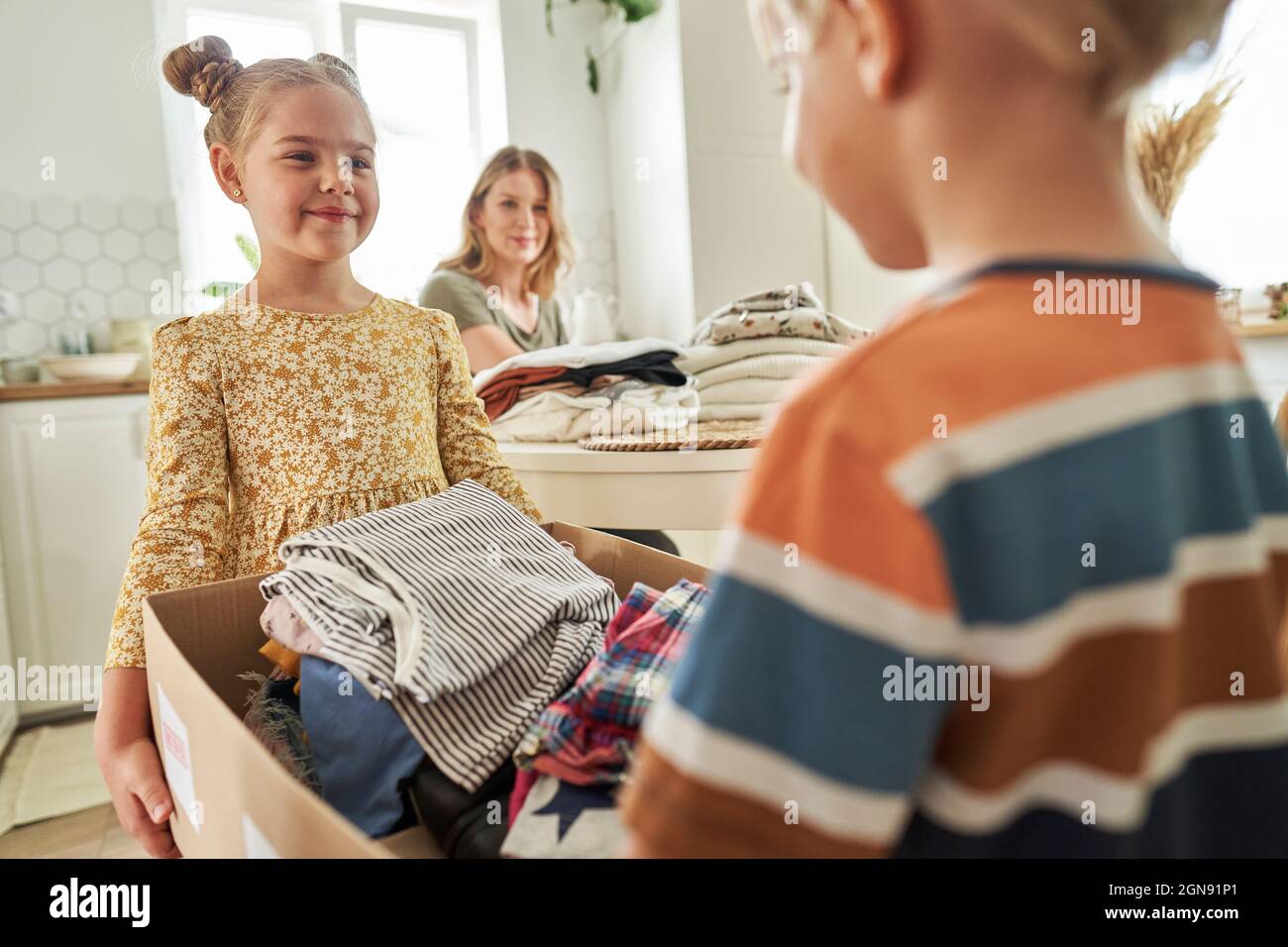 Children carrying donation box with mother in background at home Stock ...