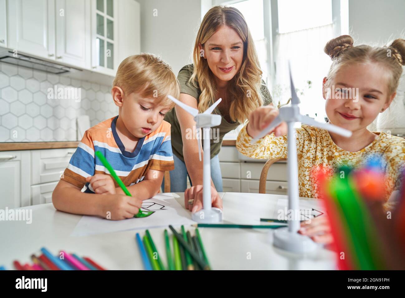 Mother teaching children about wind turbine model at table Stock Photo ...