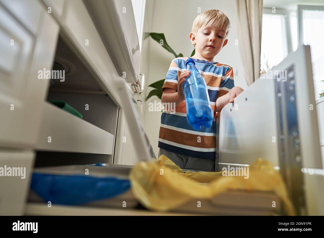 Blond boy throwing plastic bottle in garbage bin Stock Photo - Alamy