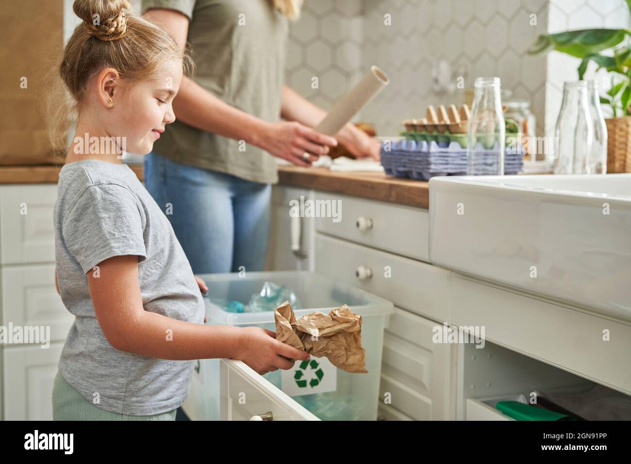 Girl collecting garbage in recycling bin at home Stock Photo - Alamy