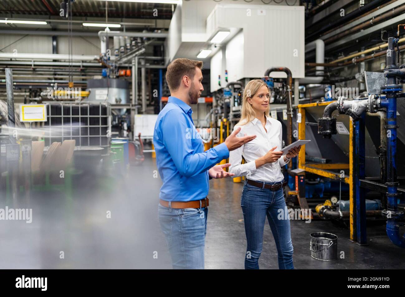 Male professional pointing while explaining colleague in factory Stock ...