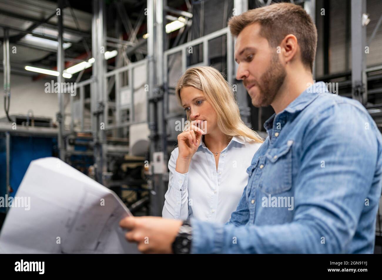 Business professionals brainstorming over plan in factory Stock Photo ...