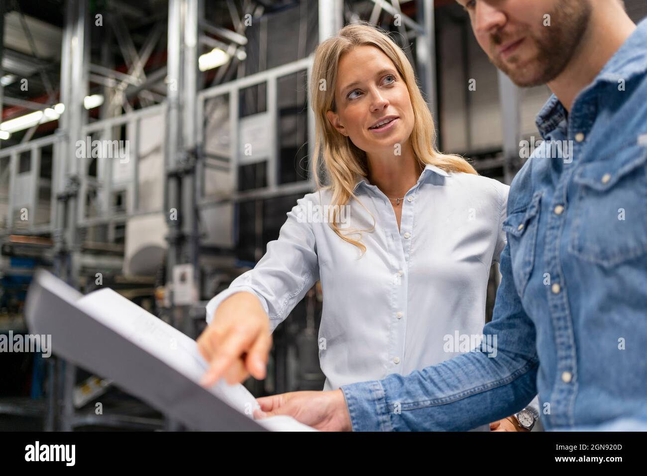 Businesswoman sharing expertise with colleague over plan at industry ...