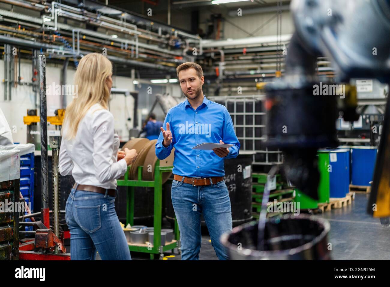 Male professional sharing expertise with female colleague in factory ...