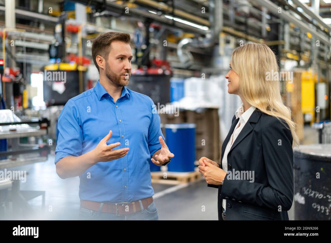 Male professional discussing with female coworker at factory Stock ...