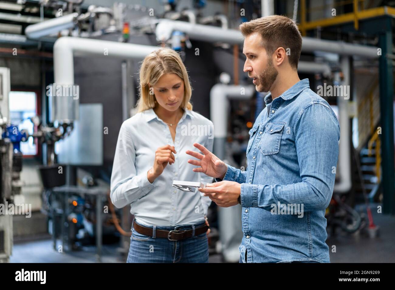 Male professional explaining over equipment to female coworker at ...