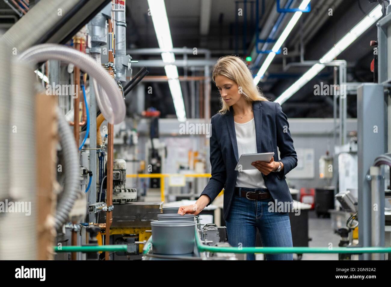Female manager with digital tablet checking production line in factory ...