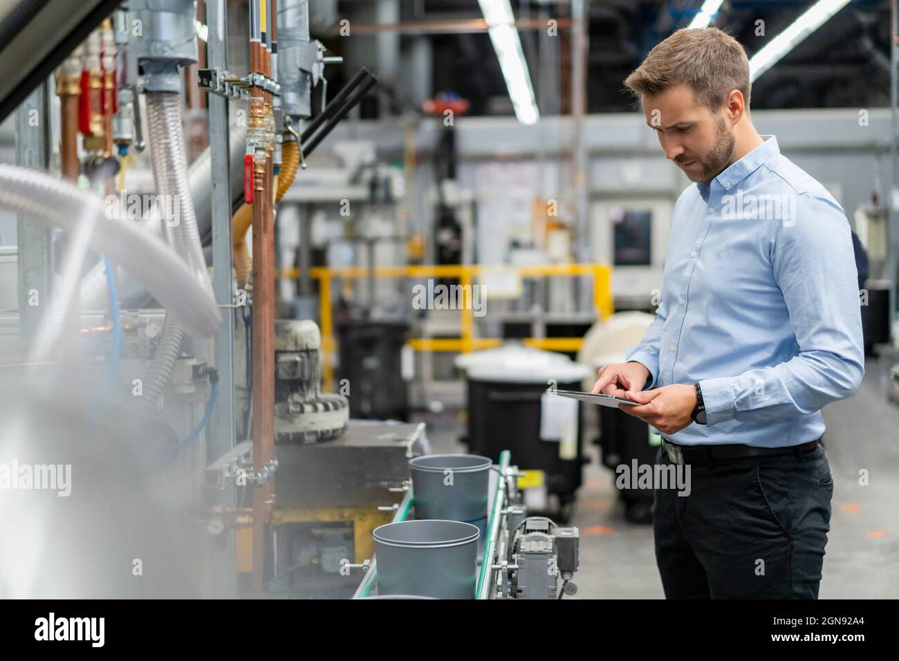 Male inspector with digital tablet checking production line in factory ...