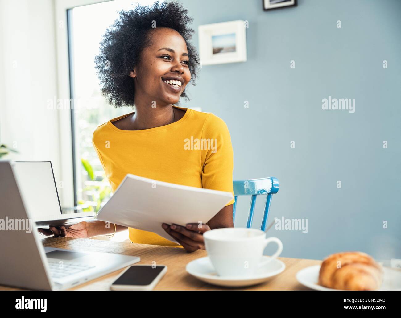 Happy female professional holding documents at desk Stock Photo - Alamy
