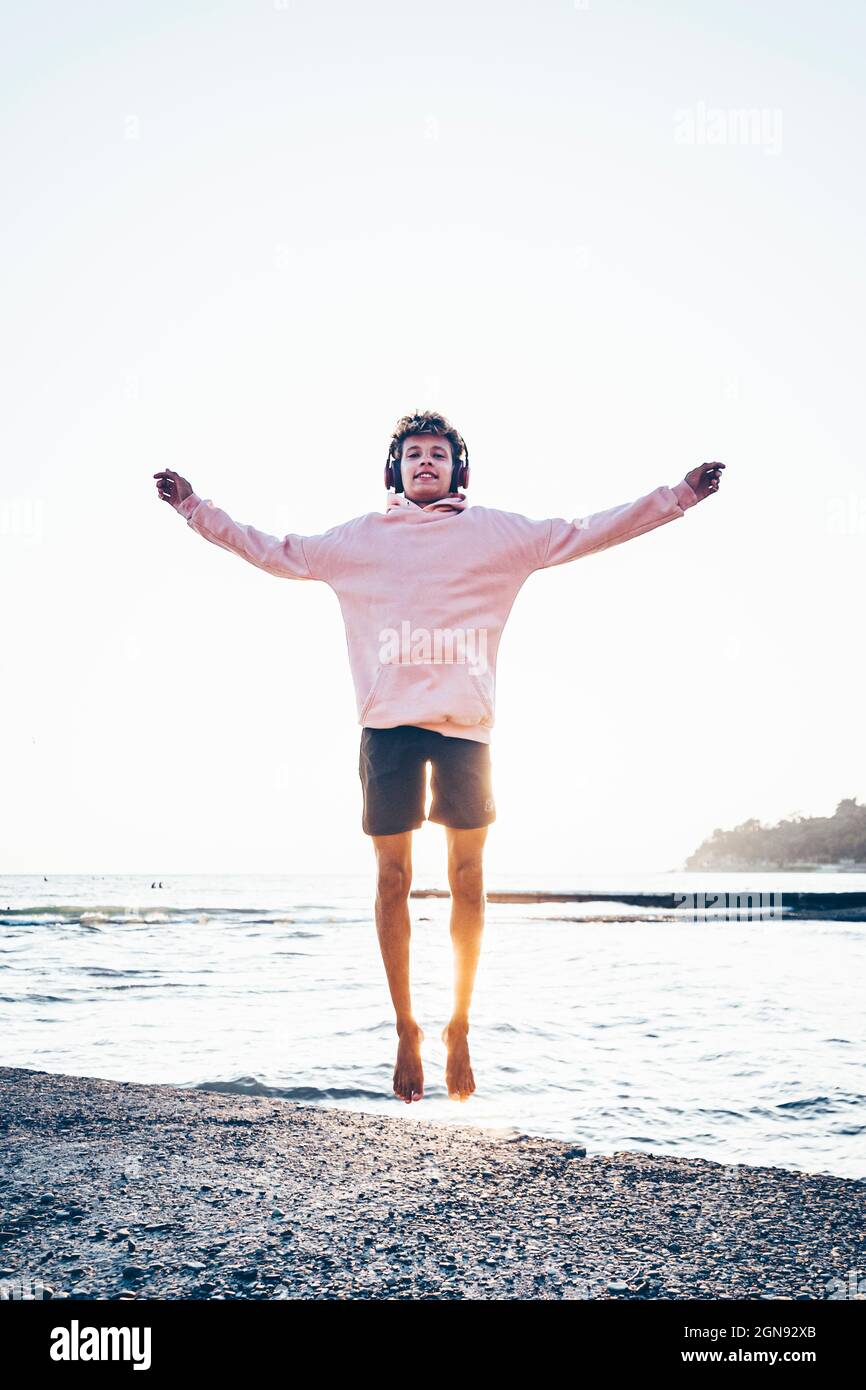 Carefree young man jumping at beach Stock Photo - Alamy