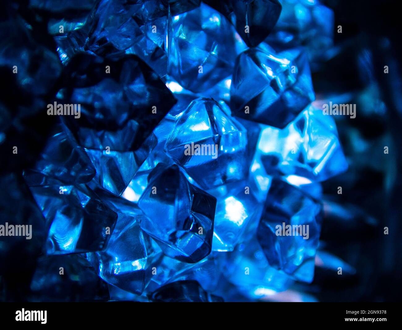 Bright blue crystals made of glass look like gems close-up in the blur ...