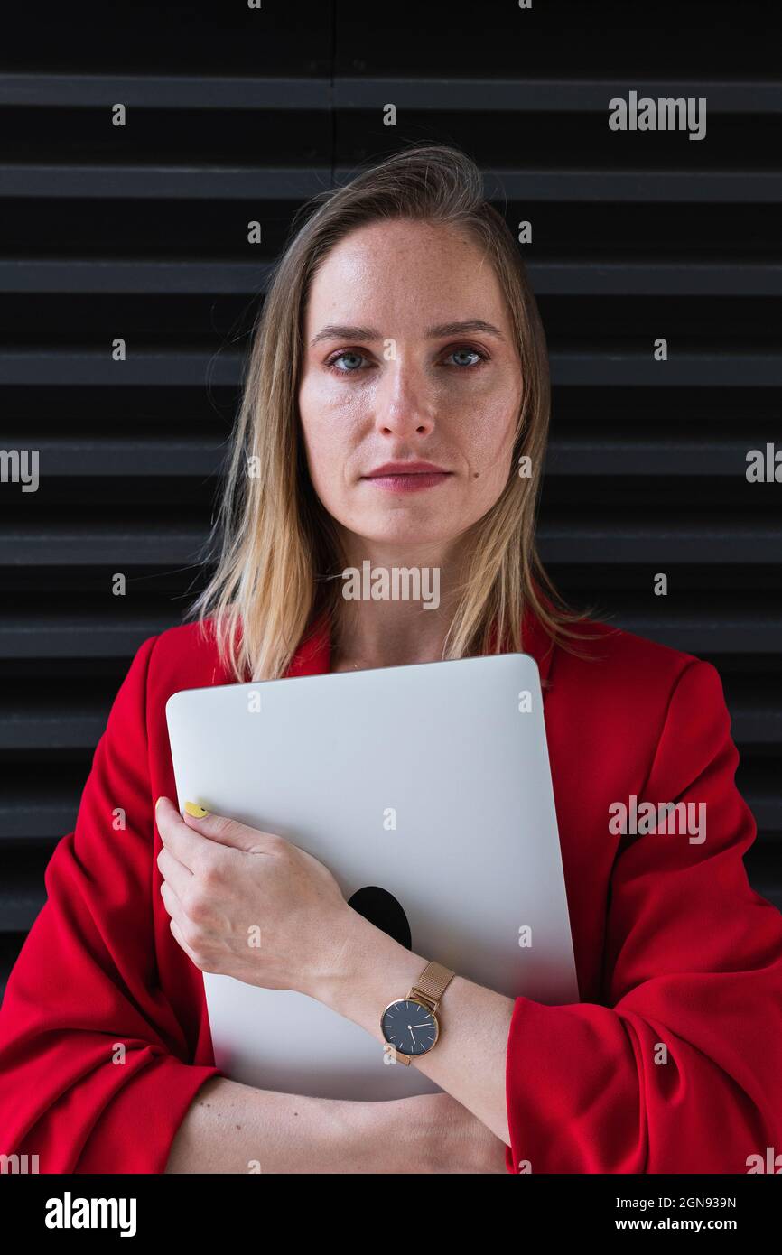 Female professional holding laptop in front of black shutter Stock ...