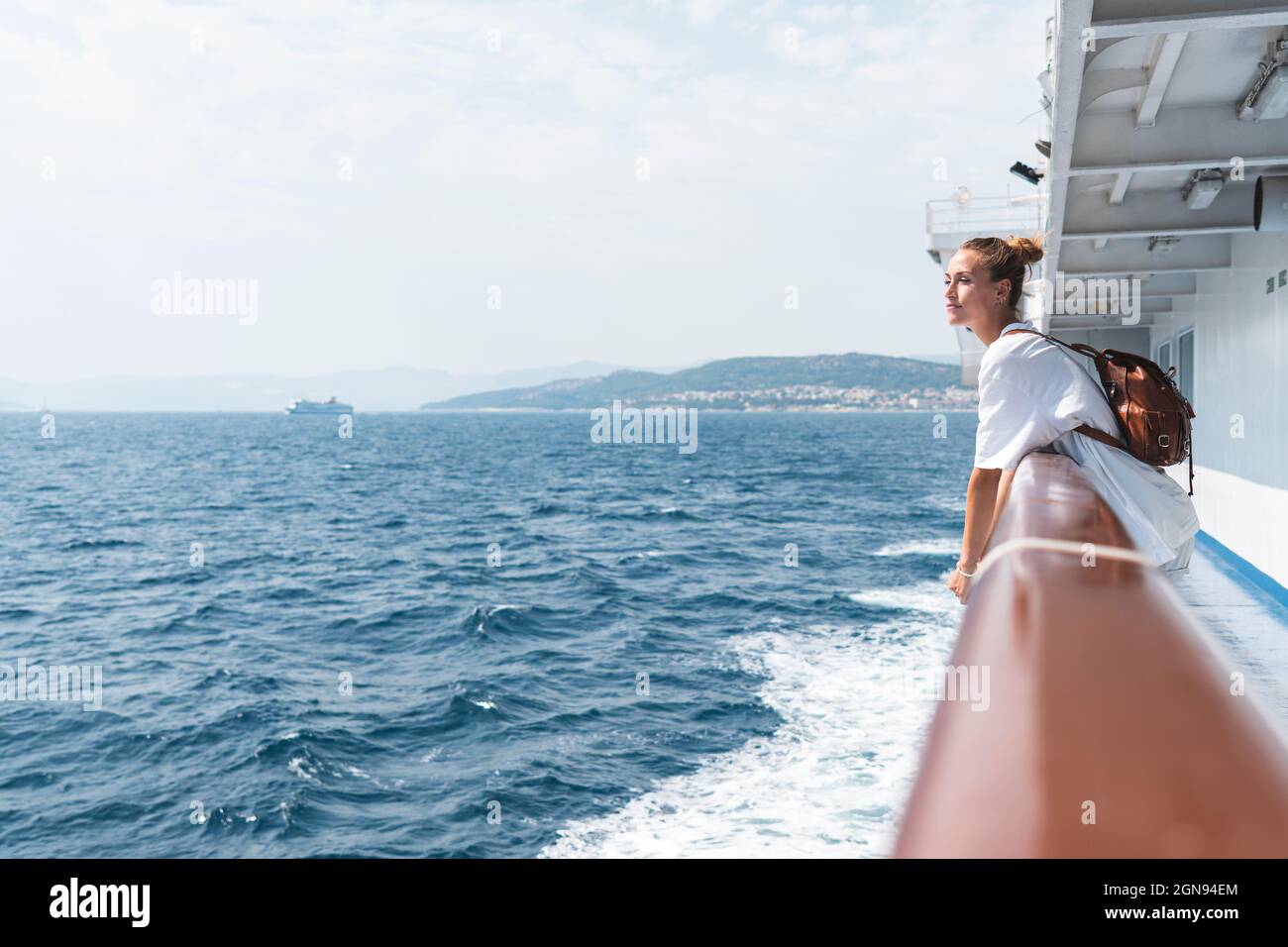 Woman with backpack leaning on railing while traveling by boat Stock ...