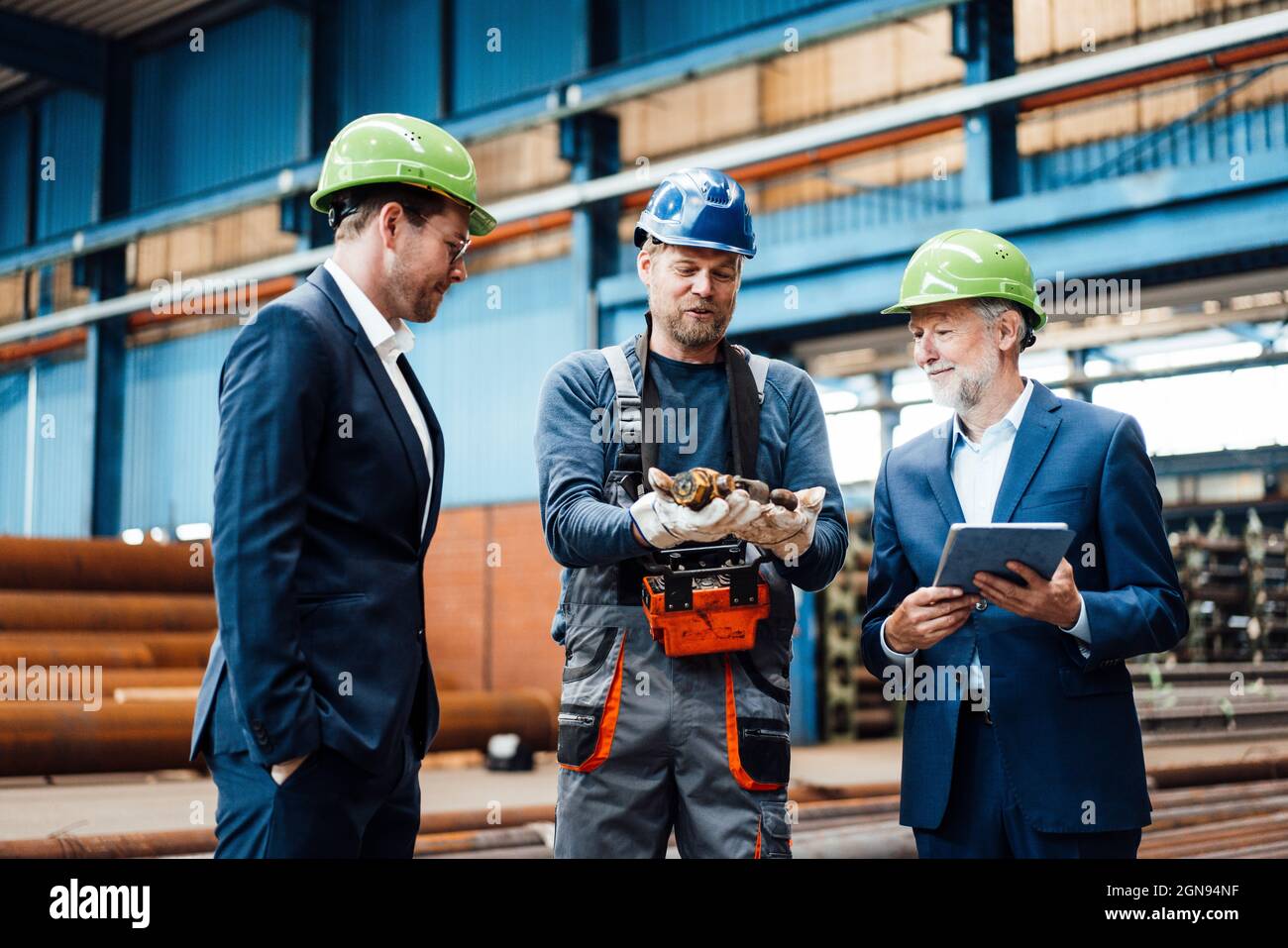 Senior and junior managing directors having discussion with coworker at ...