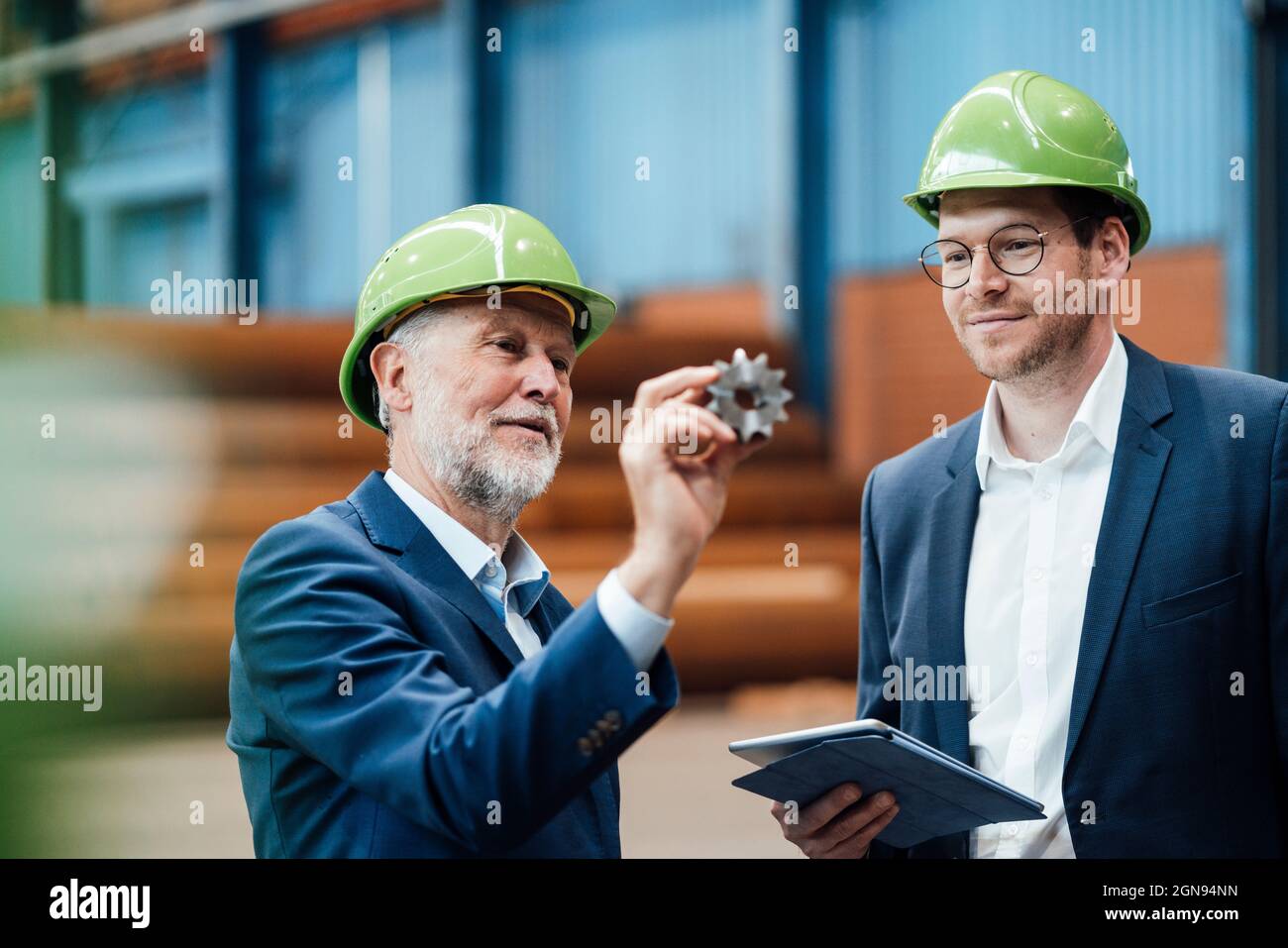 Businessman sharing expertise with coworker over equipment in industry ...