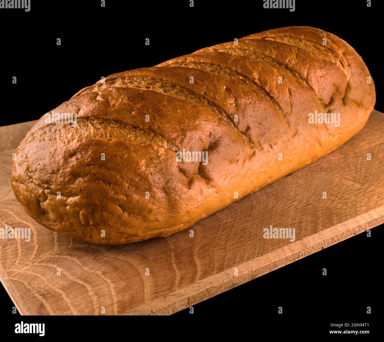 Whole loaf of bread on a wooden board on a black background Stock Photo ...