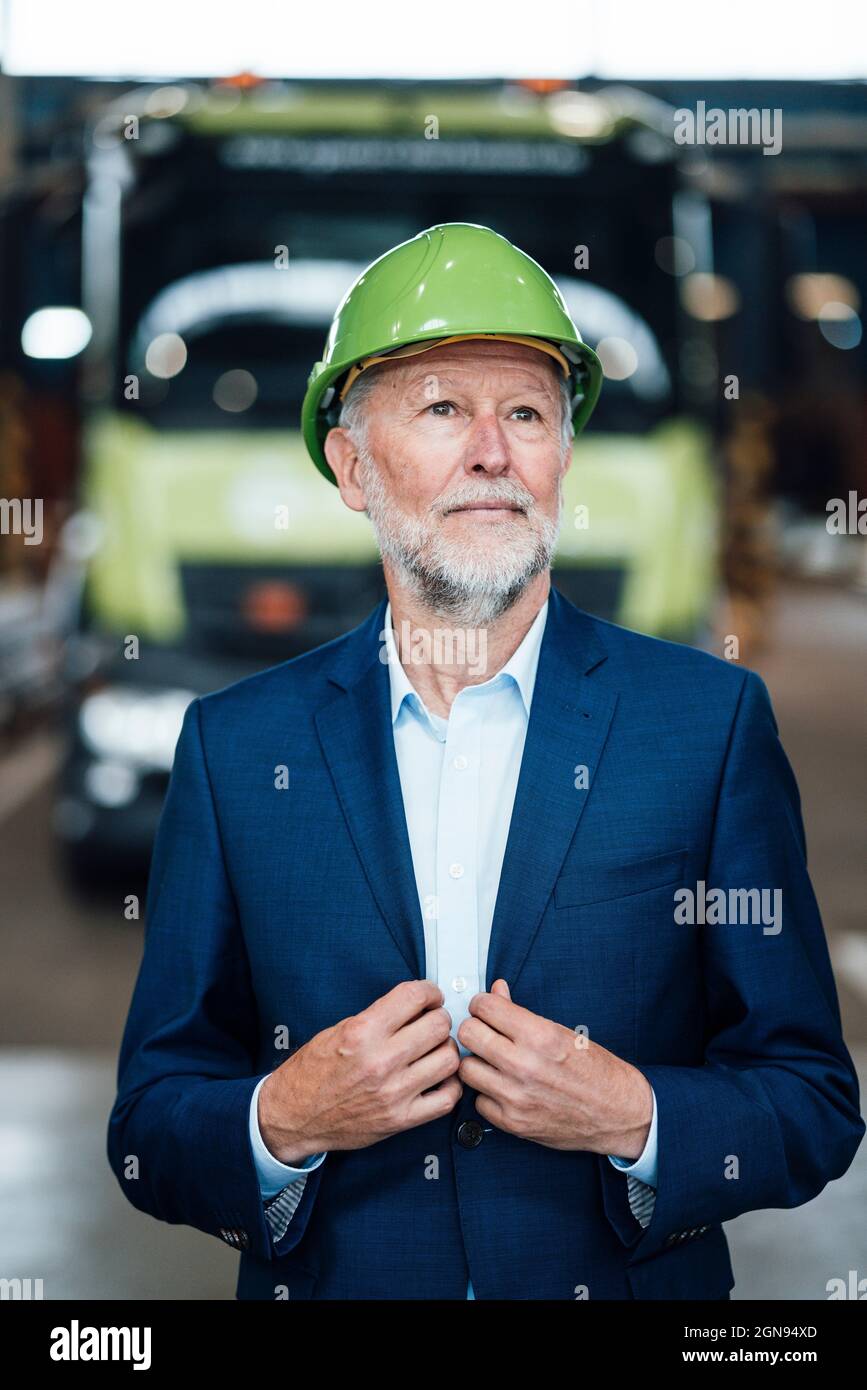 Smiling male managing director standing with hands in pockets at ...
