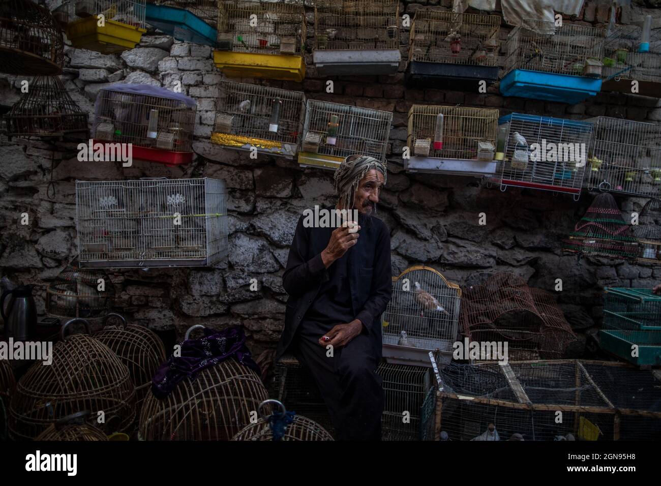 Kabul, Afghanistan. 23rd Sep, 2021. An Afghan bird vendor smokes a ...