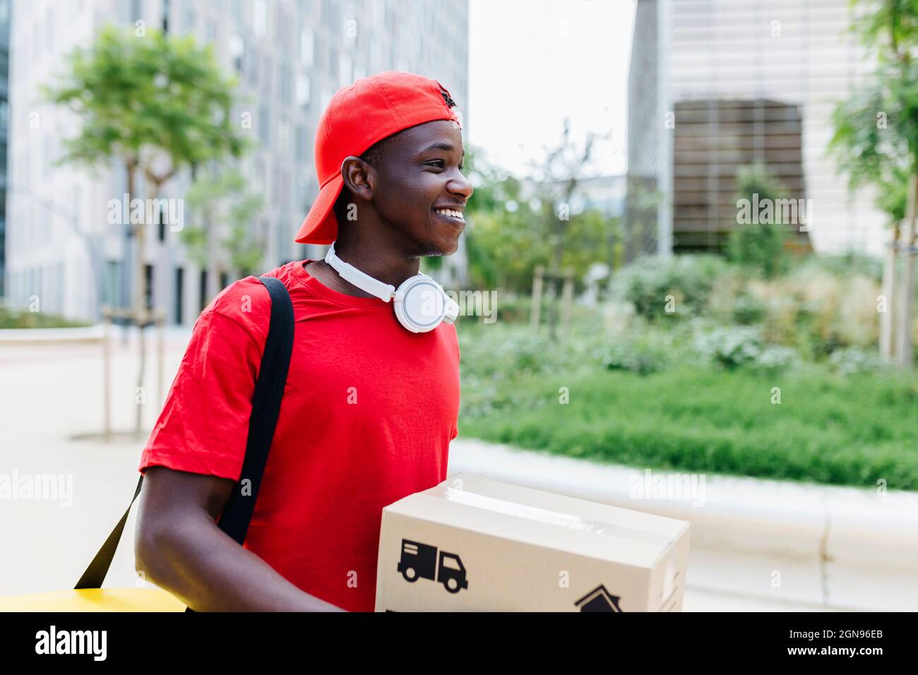 Happy young delivery man carrying box Stock Photo - Alamy