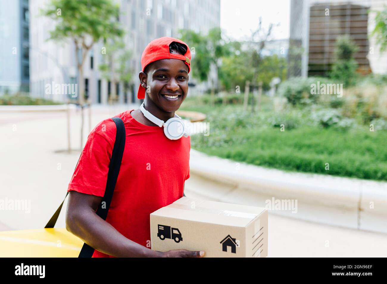 Smiling young delivery man carrying package Stock Photo - Alamy