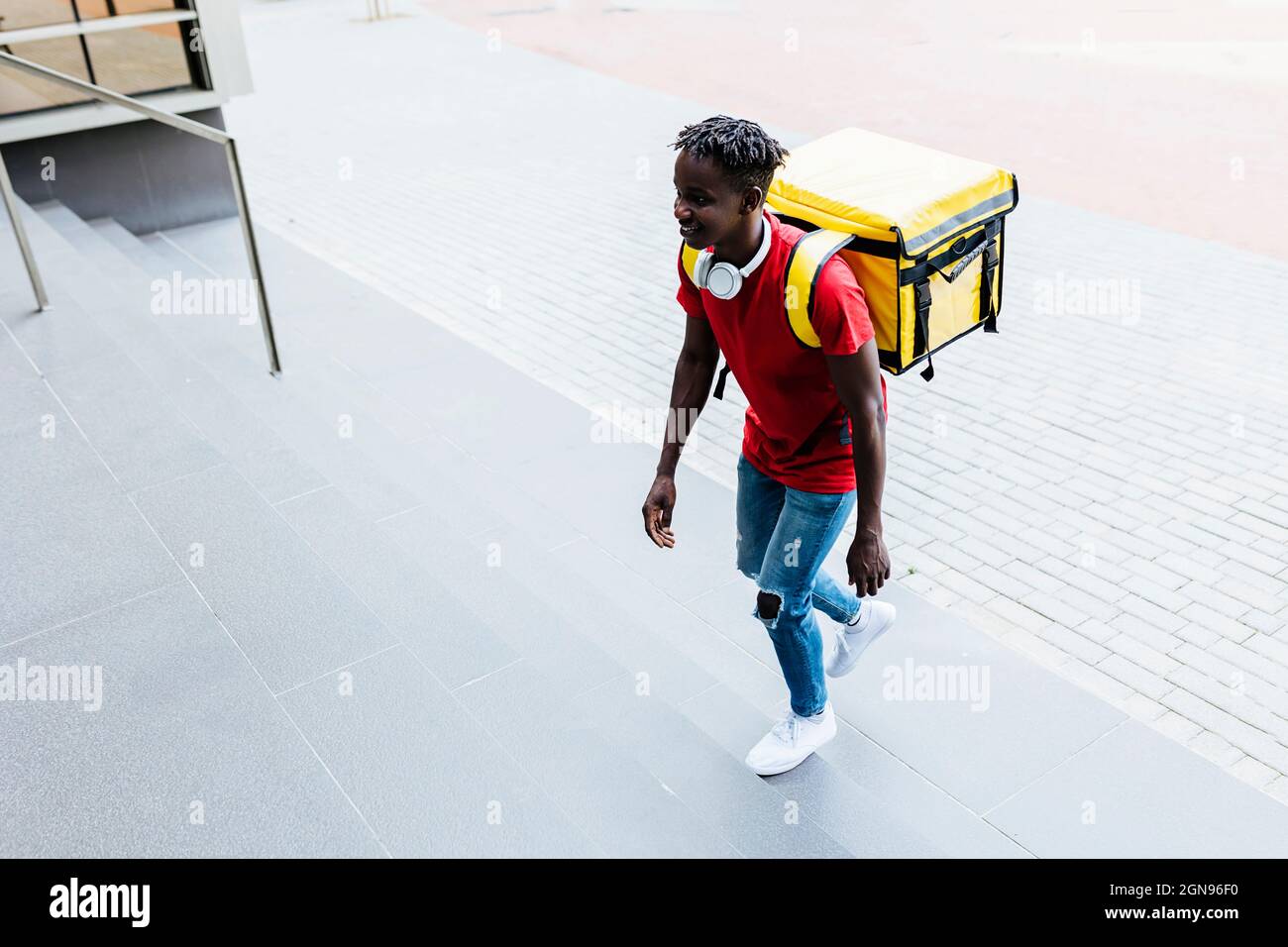 Young delivery man wearing backpack moving up on steps Stock Photo - Alamy