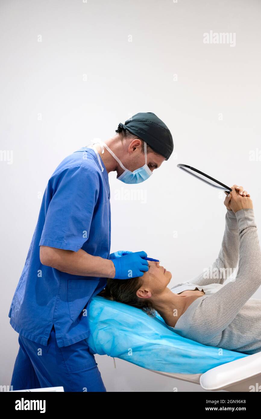 Female patient looking herself in the mirror, lying on the stretcher ...