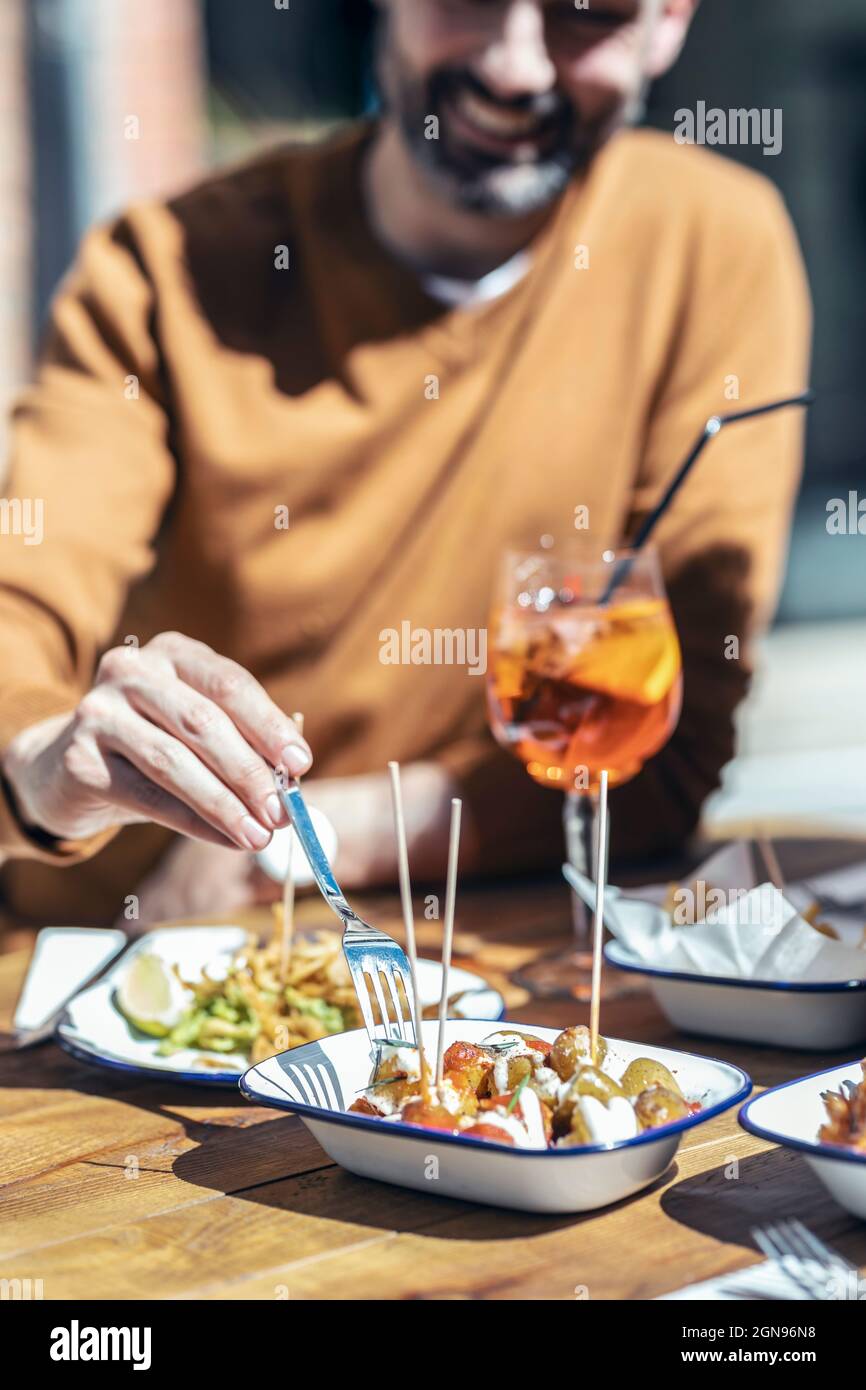 Smiling man eating tapas at restaurant Stock Photo - Alamy