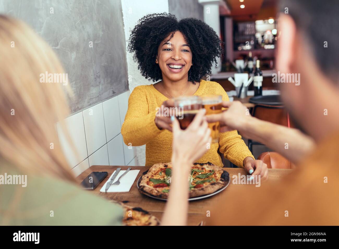 Happy young woman raising toast with male and female friends in ...