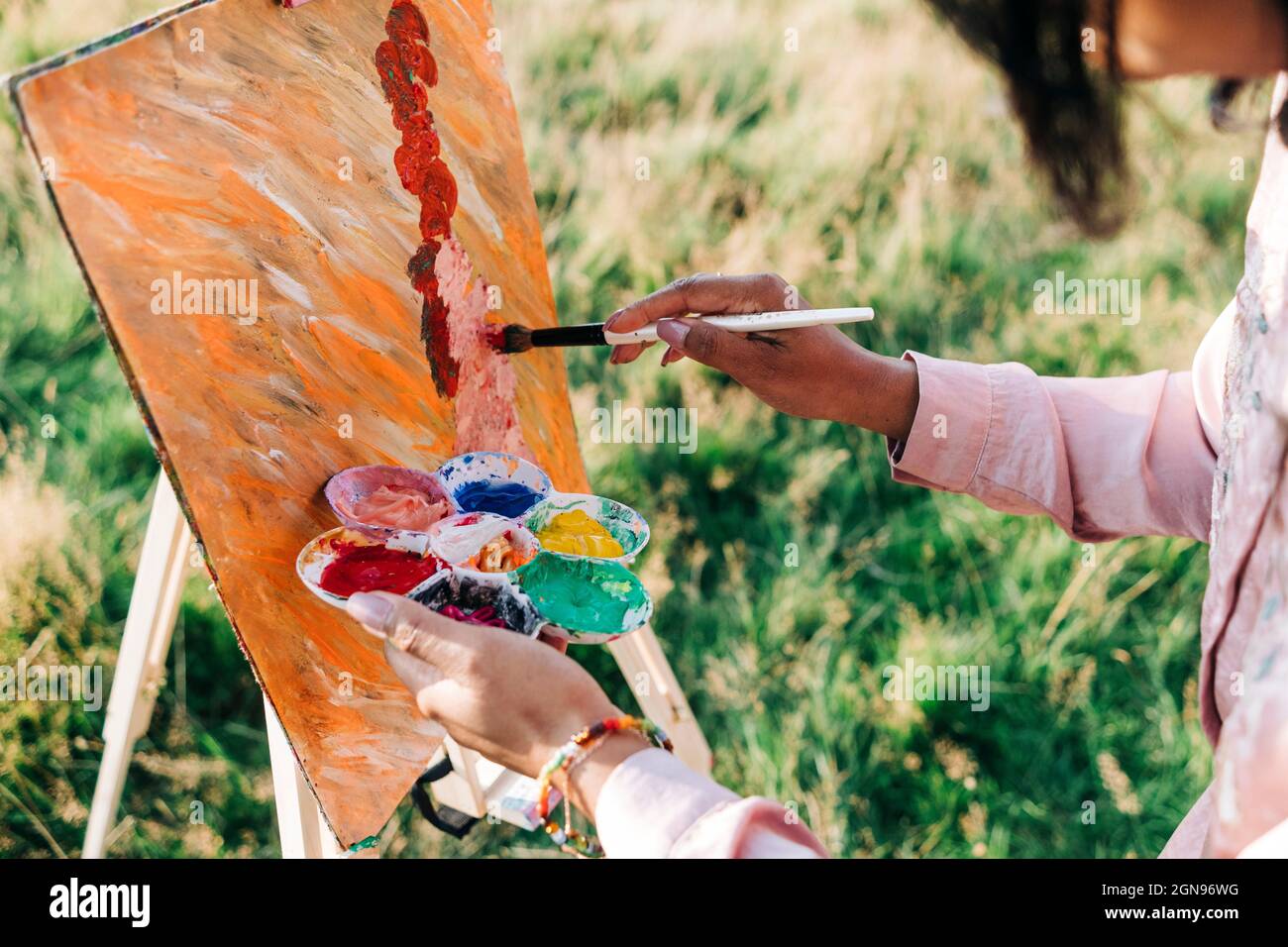 Mid adult woman holding paint palette while painting at park Stock ...