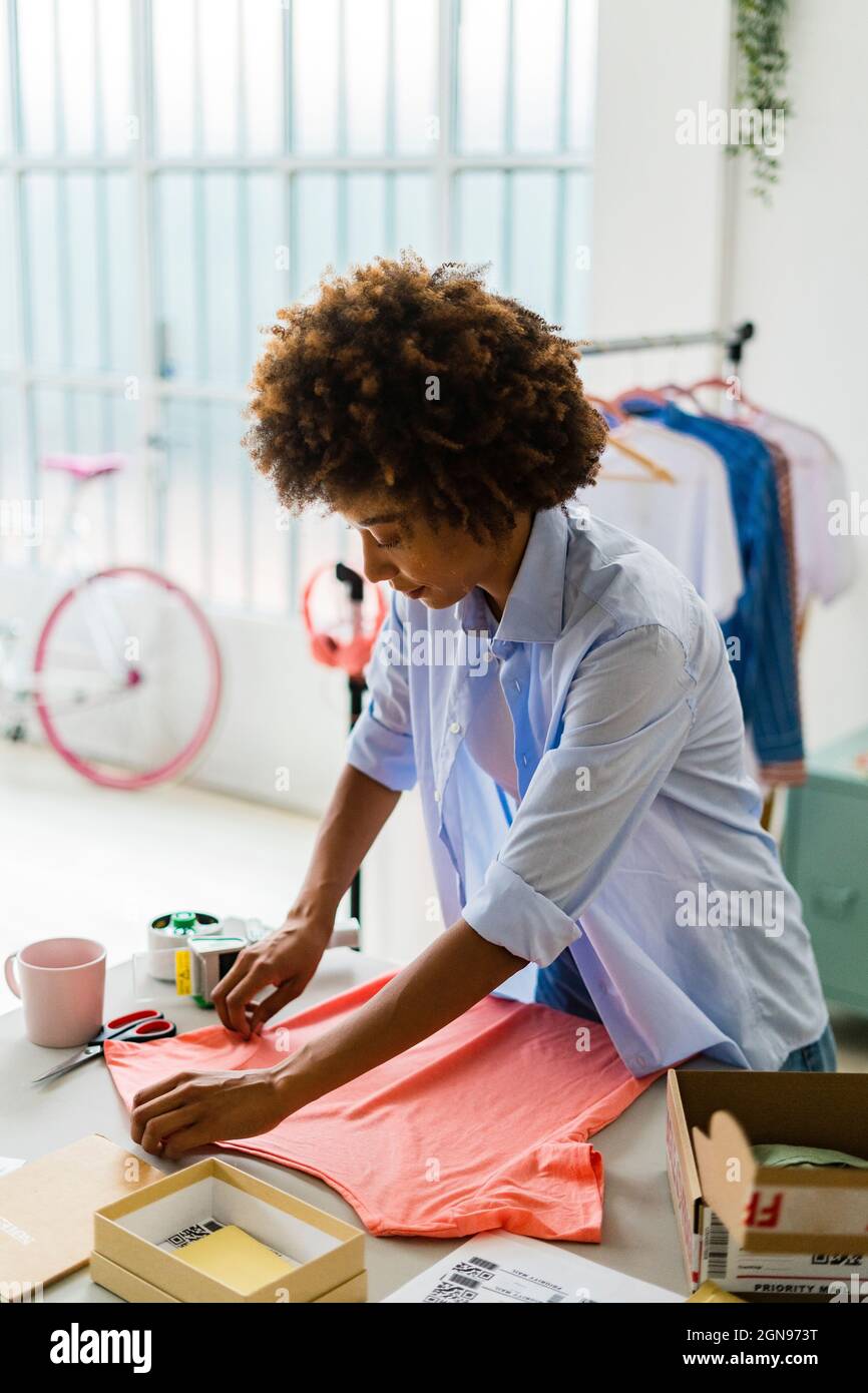 Female fashion designer folding dress on desk at studio Stock Photo - Alamy