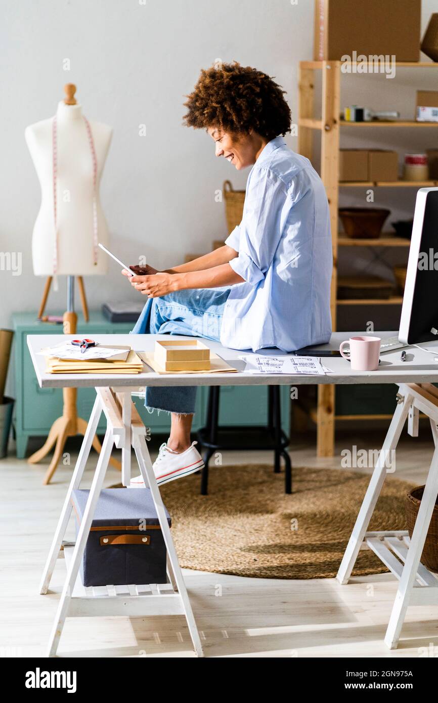 Confident female fashion designer with arms crossed standing at studio ...