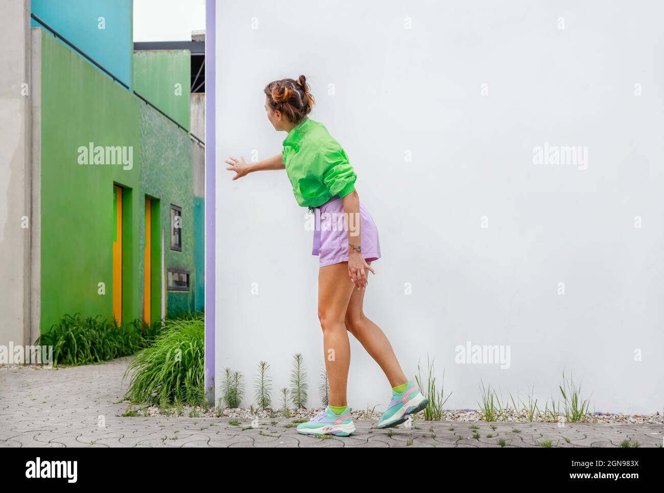Young woman standing on footpath in front of white wall Stock Photo - Alamy
