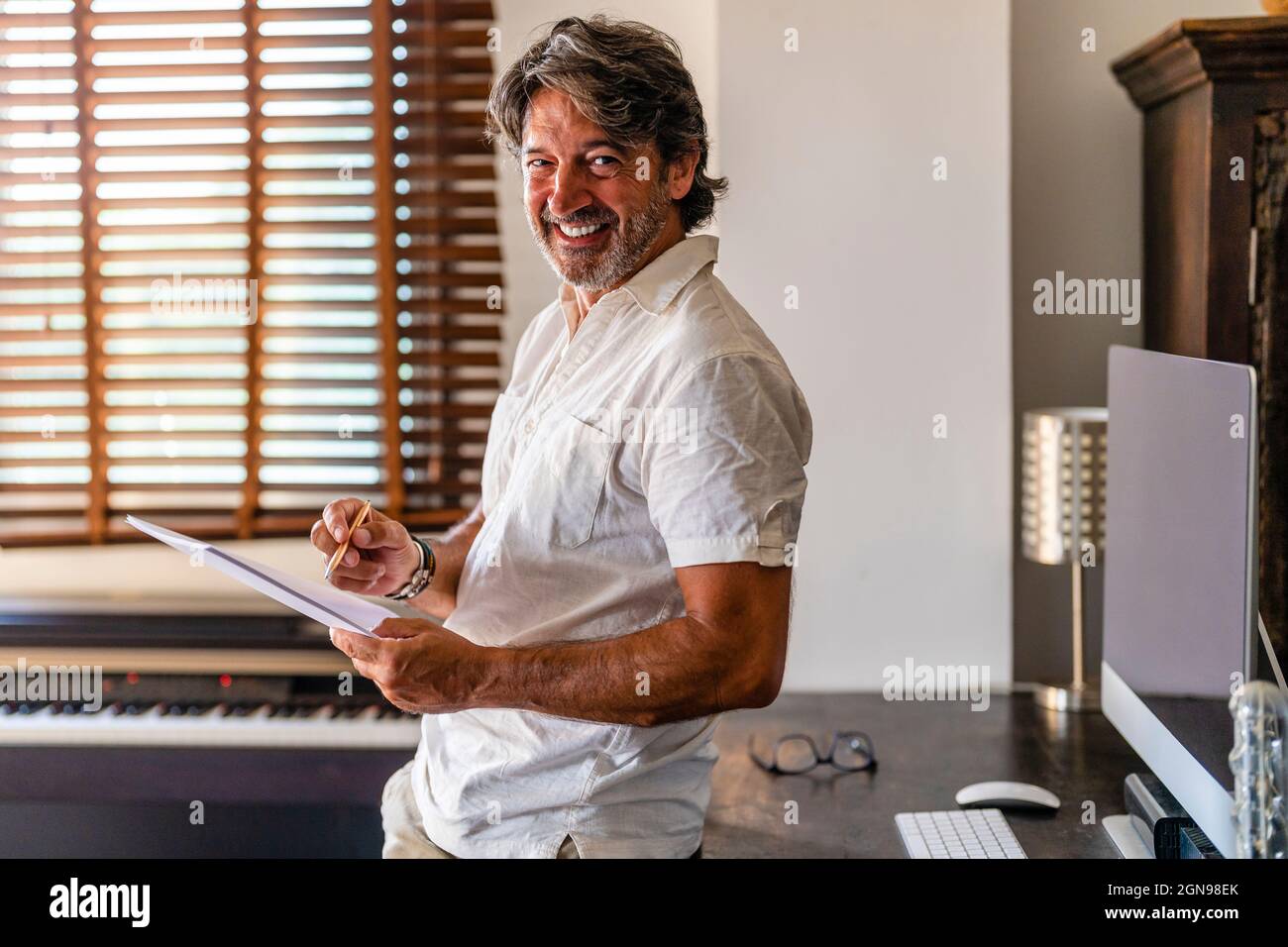 Male professional holding pen and paper at home office Stock Photo - Alamy