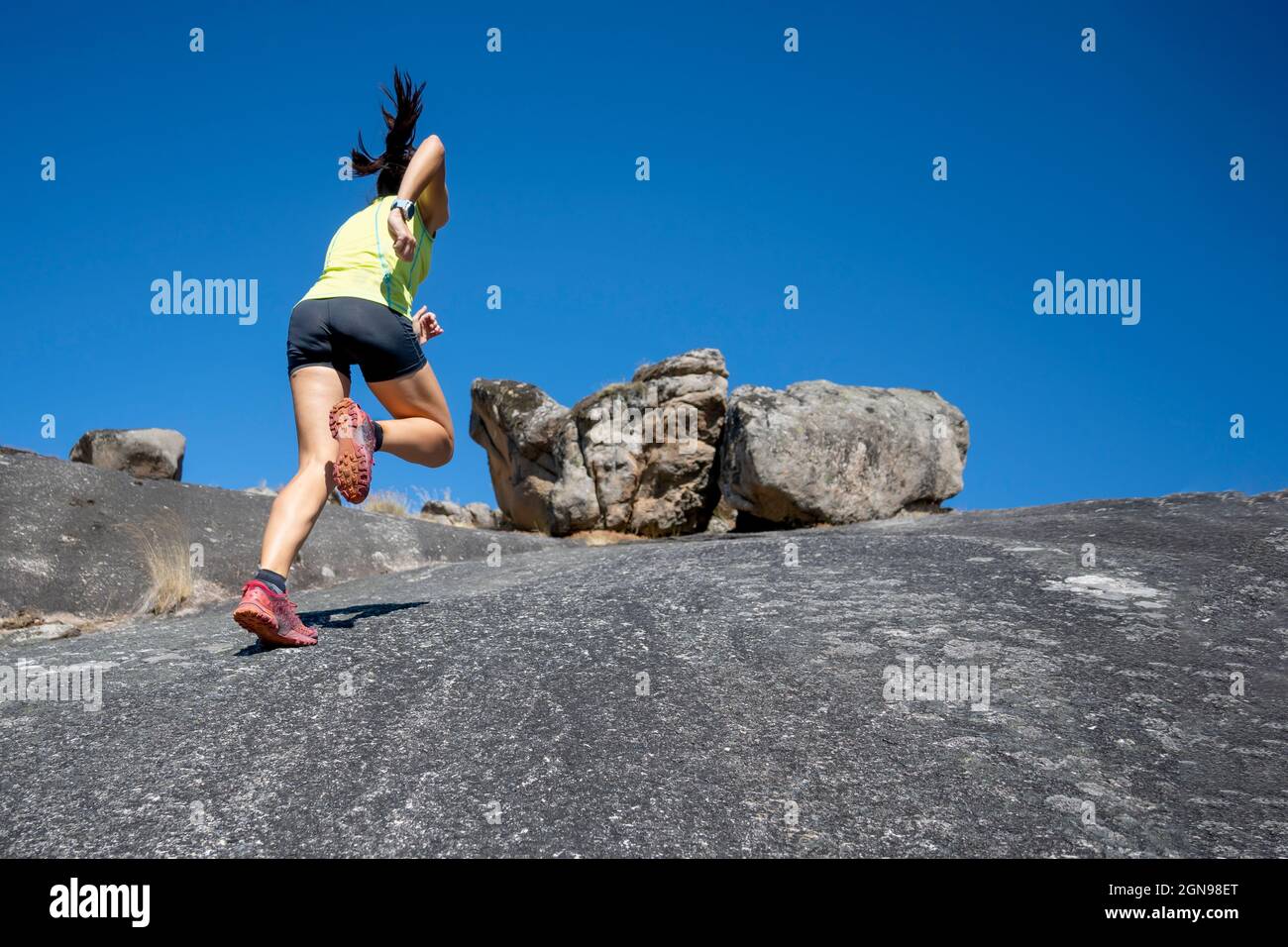 Female athlete running up on rock mountain during sunny day Stock Photo ...