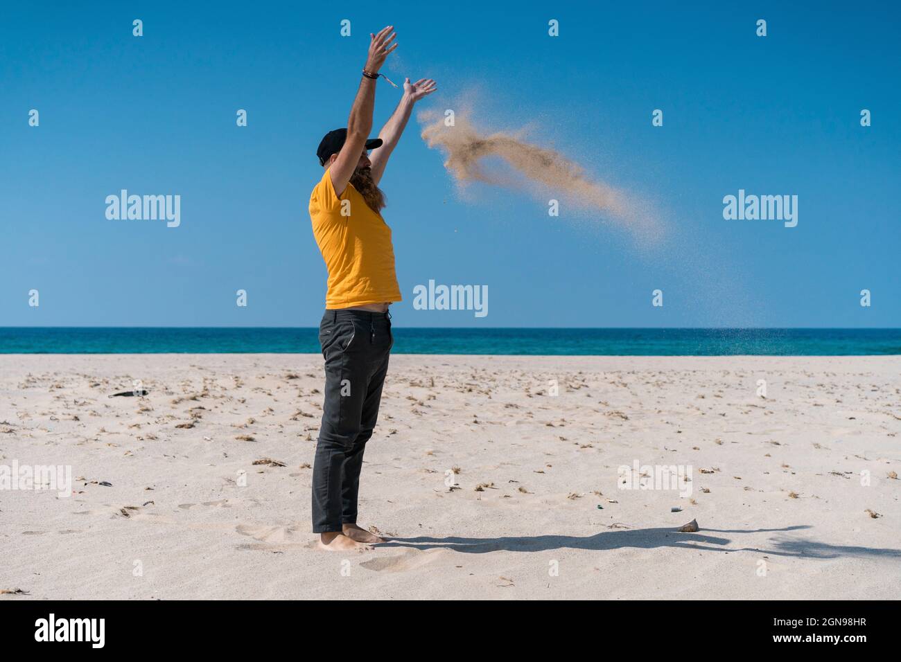 Man throwing sand while standing at beach Stock Photo - Alamy