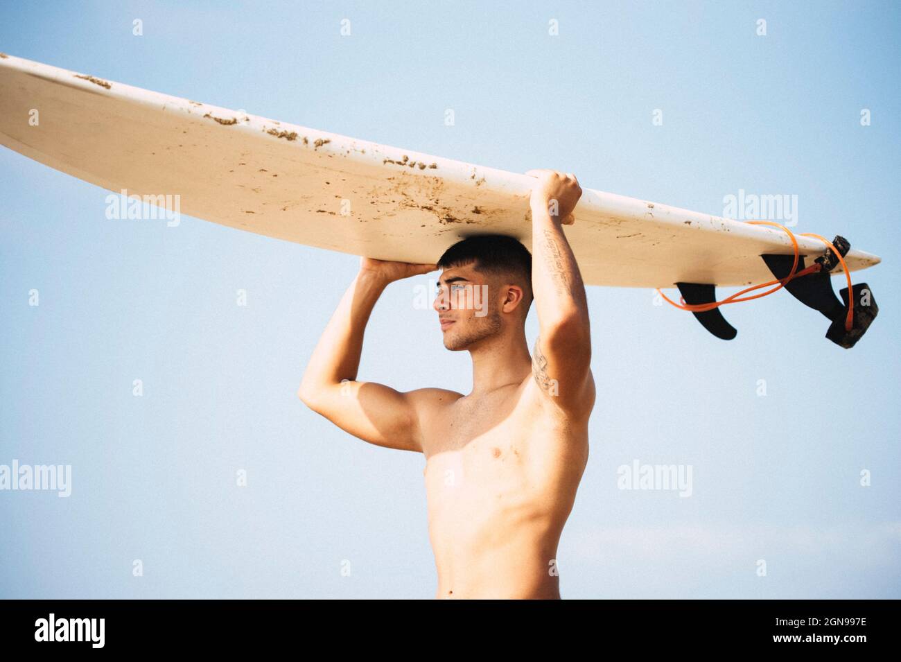 Side view of surfer holding a surfboardwhile looking out to sea Stock ...