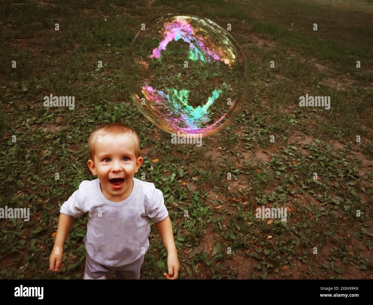 Happy boy smiling and looking at soap bubble outdoors Stock Photo - Alamy
