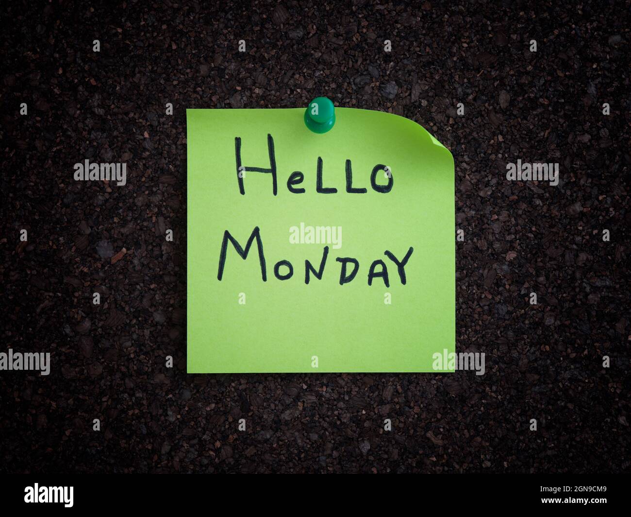 A sticky note with the greeting Hello Monday on it pinned to a cork ...