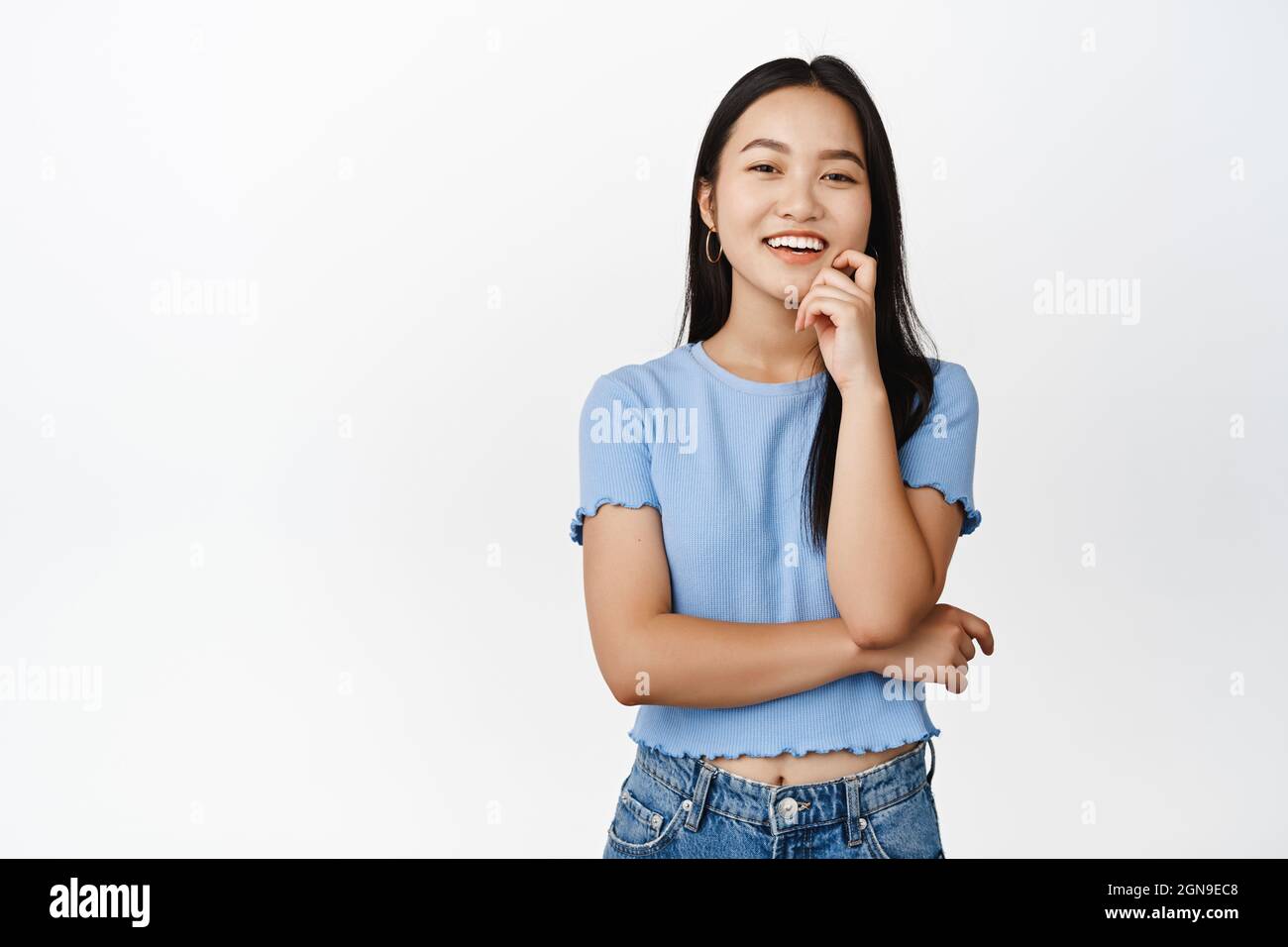 Smiling asian female student looking thoughtful, intrigued by something ...