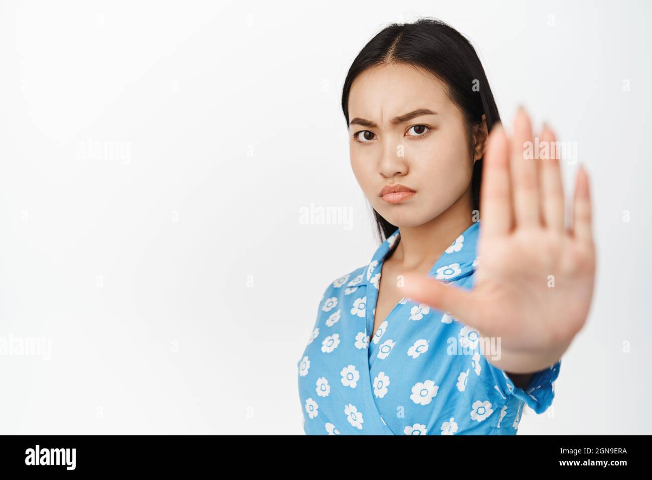 Close up of serious asian woman stretch out hand and say no, stop ...