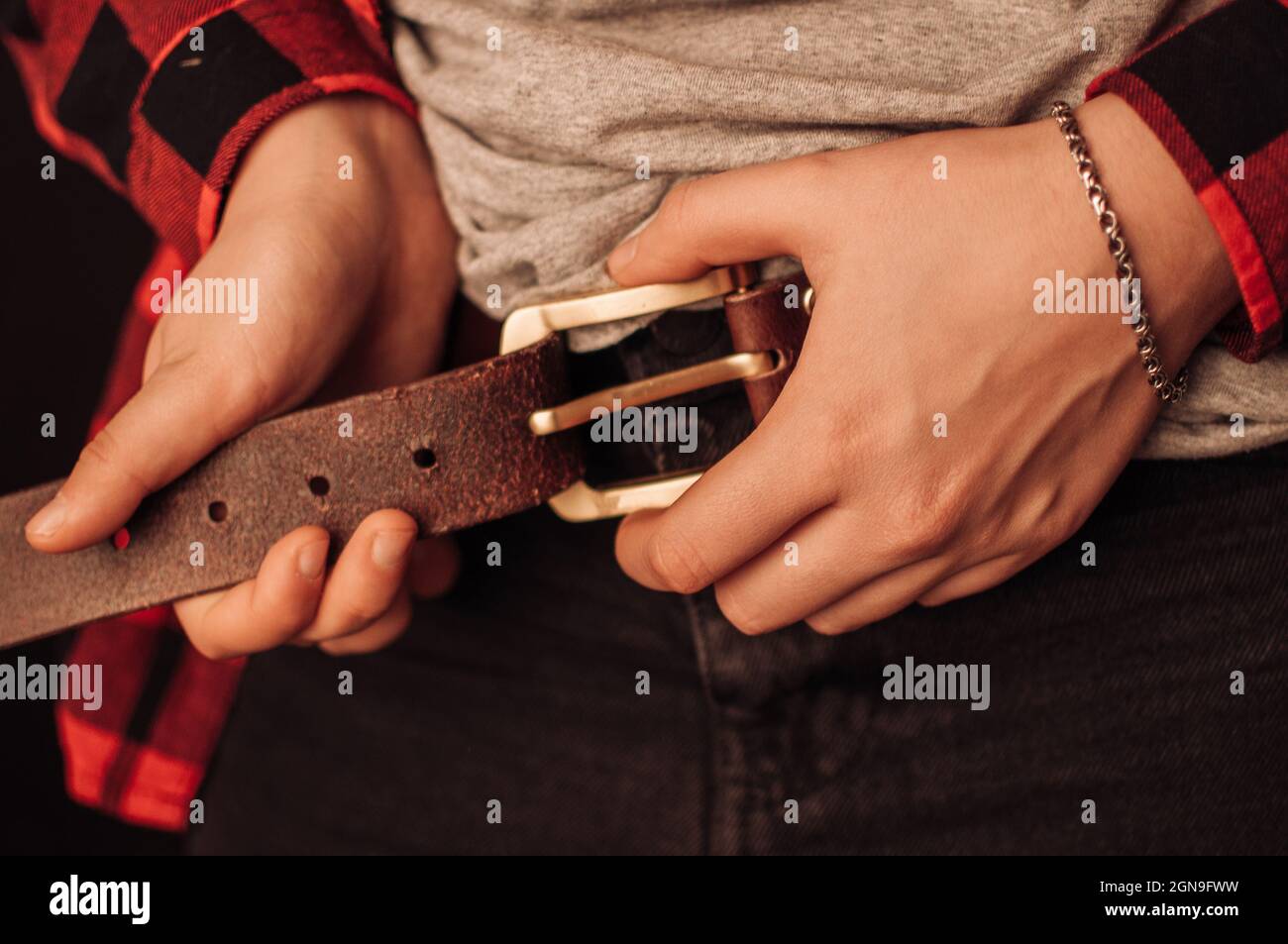 Man putting on an old leather belt Stock Photo - Alamy