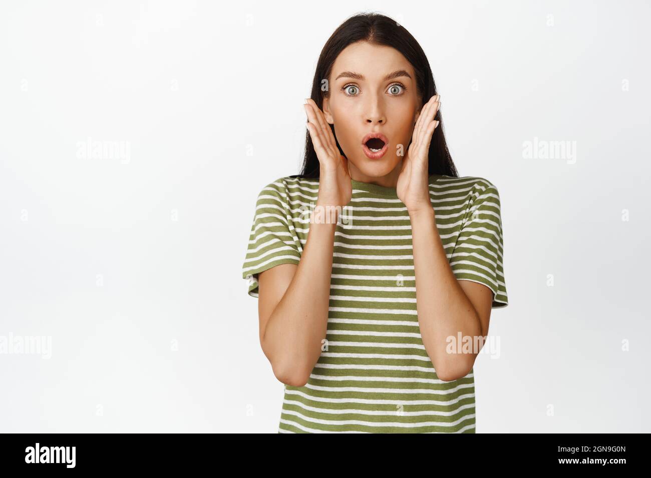 Image of young brunette woman gasping, looking shocked and startled ...