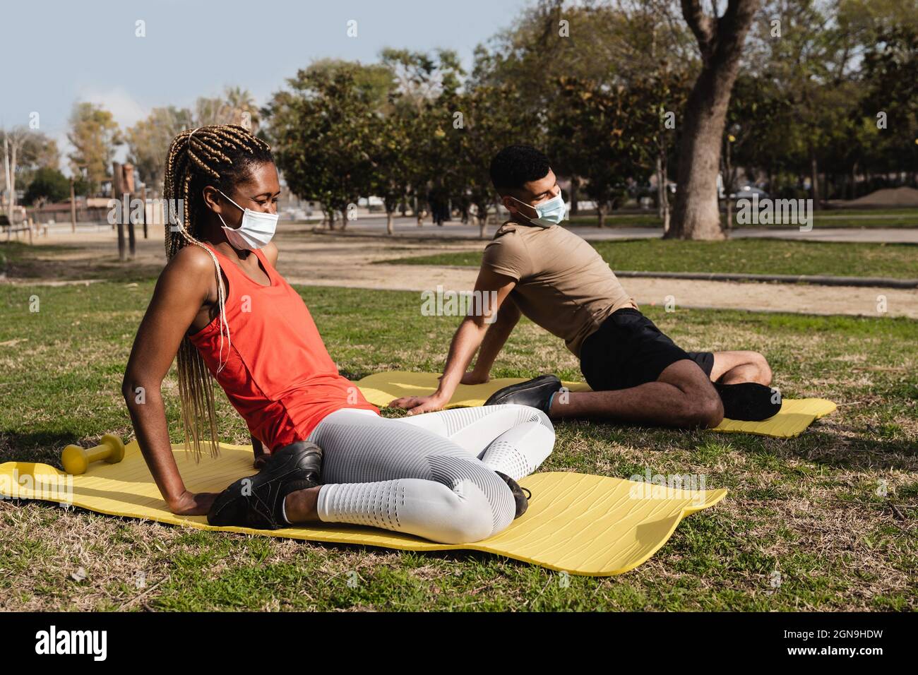 Black people doing yoga routine outdoor while wearing safety masks ...